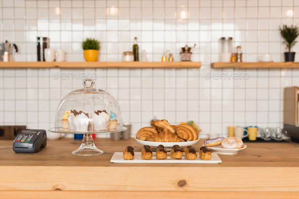 bar counter with cake stand and dishes with delicious desserts and ...