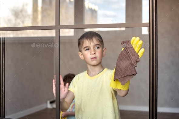 The boy washes the window. House cleaning, help, housework. The child ...