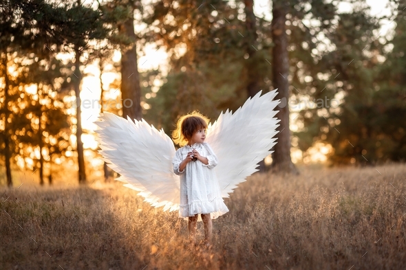 Cute little child angel in white clothes, dress and wings, standing ...