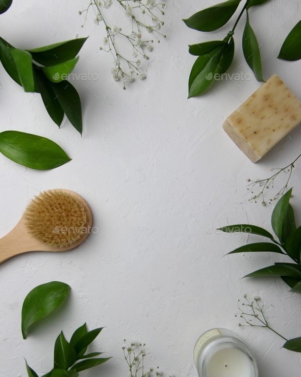 background for self-care green leaves massage brush candle and soap ...