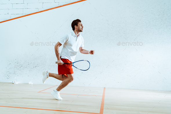 Full length view of sportsman with racket running while playing squash ...