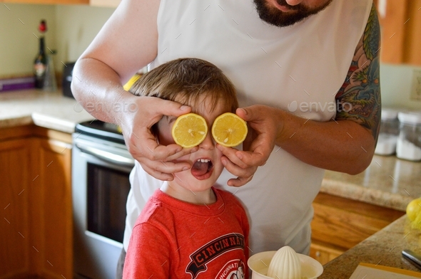 Father and son cooking and being goofy in the kitchen with lemon halves ...