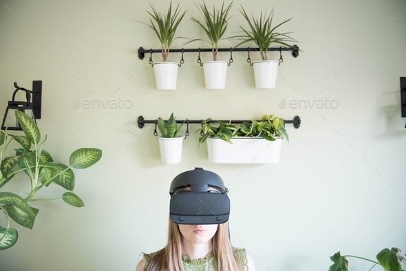 Young millennial woman wearing a virtual reality headset indoors ...