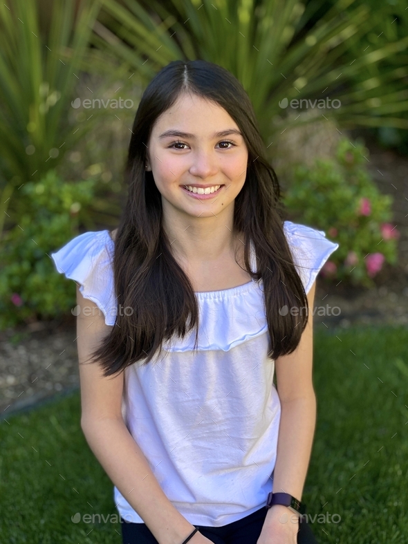 Biracial tween girl smiling for portrait with green background. Stock ...