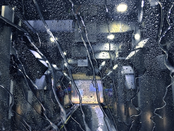 Splashes, running water on glass window inside metallic indoor space ...