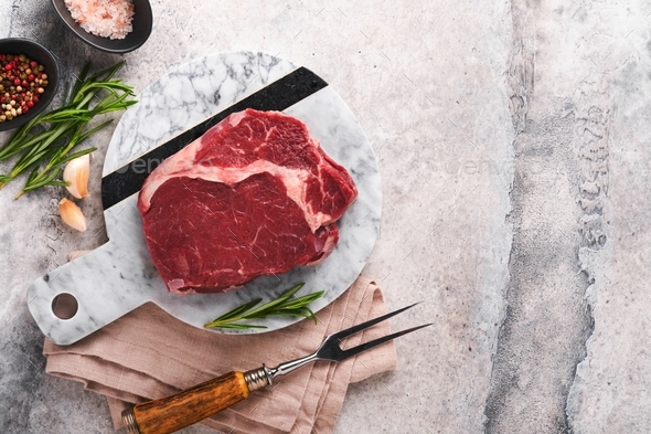 Raw beef steak. Fresh beef rib eye steak with fork rosemary, salt and ...