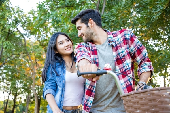 Couple in love joking together in public park with bikes on vacation in ...
