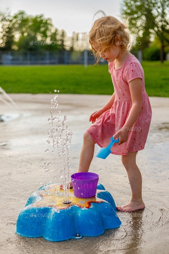 Little girl playing at splash pad playground in summer. Child at water ...
