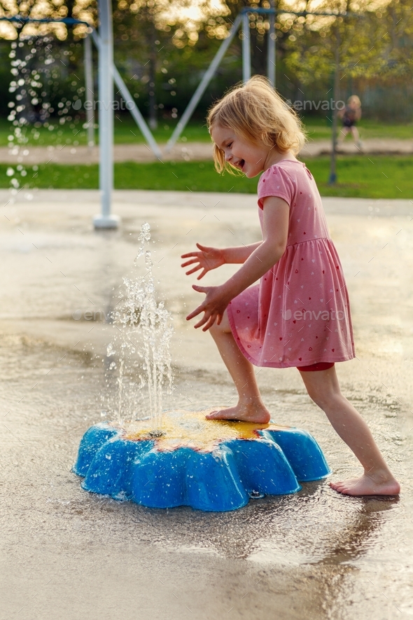 Smiling child at playground in park playing with water. Little girl at ...