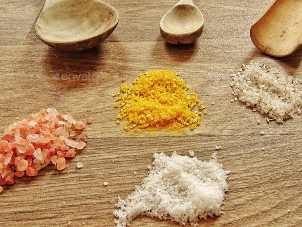Different types of sea salt on wooden background and wooden spoons ...