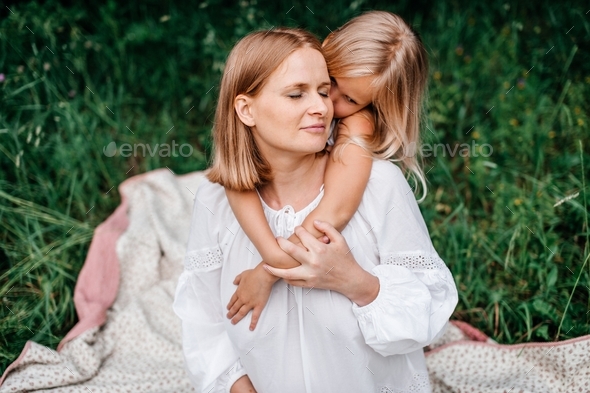A cute girl hugs her mother by the neck Stock Photo by alexandrabeganskaya