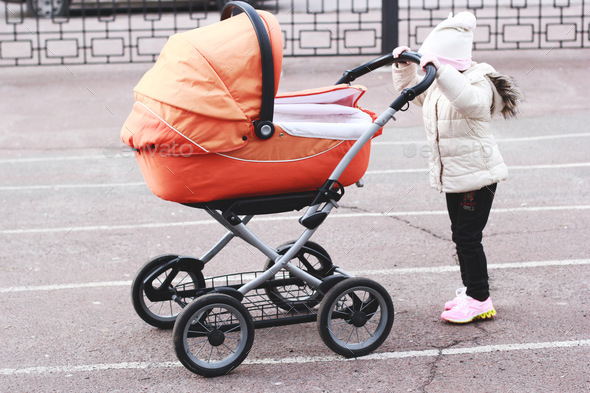 Older sister riding her little sister in the orange stroller Stock ...