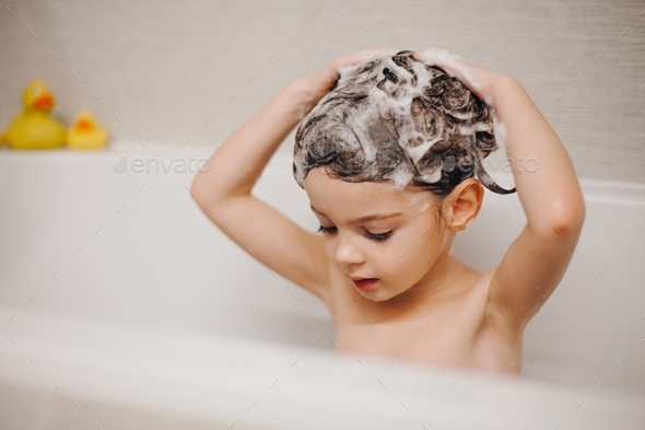 Little girl washing her head in the bathtub Stock Photo by anita_bonita