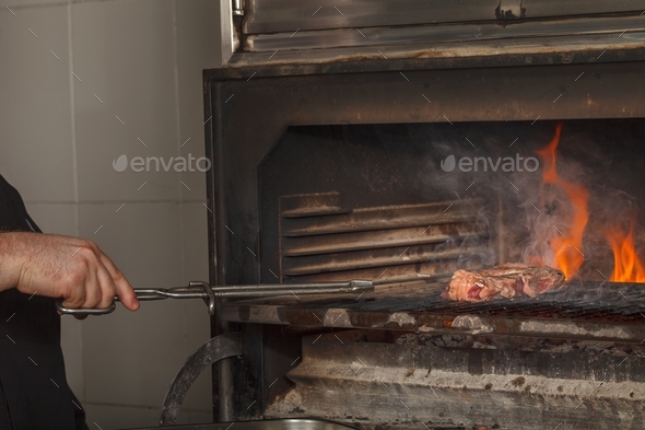 Chef makes beef steak on open fire in restaurant Stock Photo by Shandor_gor