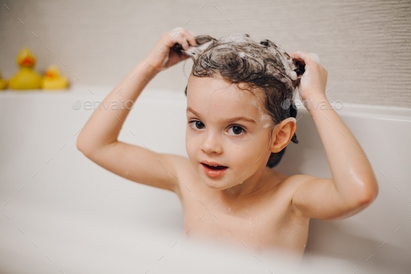 Little girl washing her head in the bathtub Stock Photo by anita_bonita