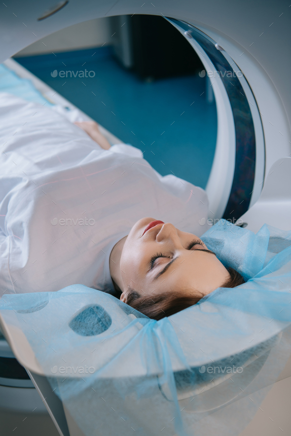 pretty woman lying with closed eyes on ct scanner bed during ...