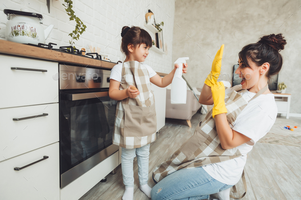 A little girl and her mother are cleaning the kitchen. a woman and a ...