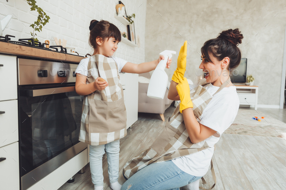 A little girl and her mother are cleaning the kitchen. a woman and a ...