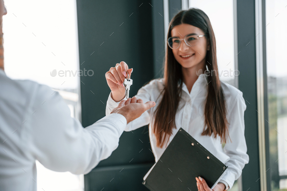Receiving keys for her new home indoors. Happy young woman with a man ...