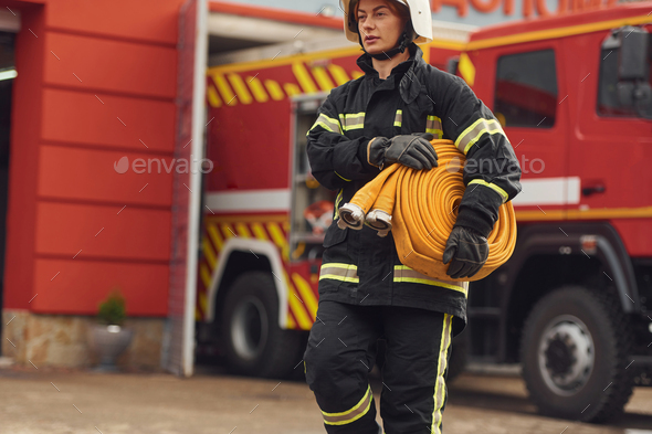Holding fire hose. Woman in uniform is at work in department Stock ...