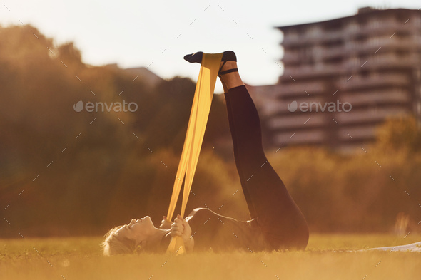 Doing exercises for the legs by using yellow colored cloth. Mature ...