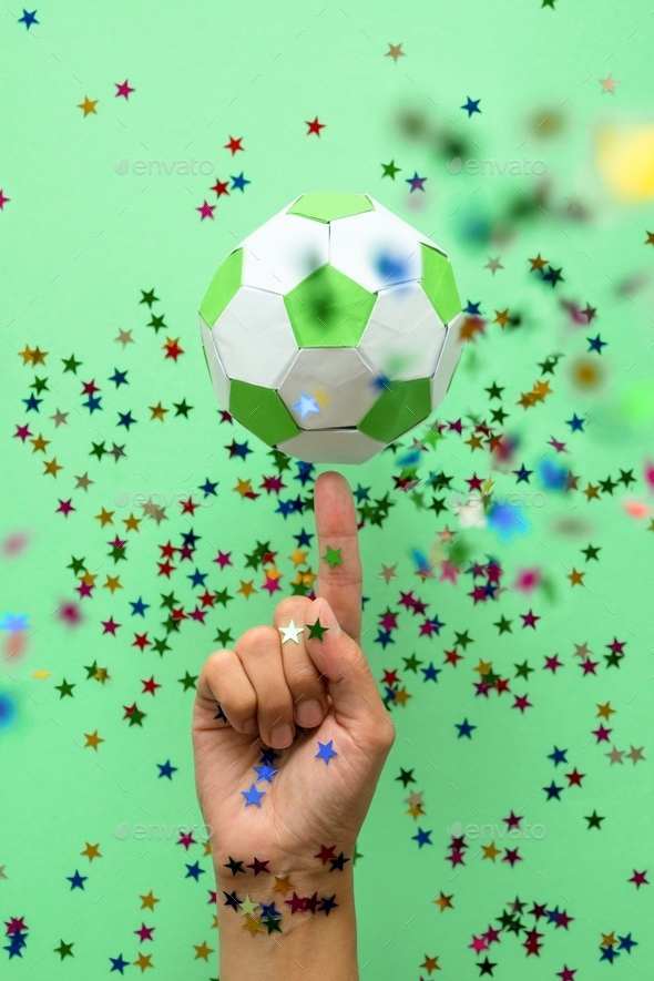 Hand spinning paper soccer ball on green background. Origami. Paper ...
