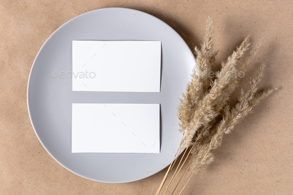 Blank white paper card on plate for mock up with dried spikelets ...