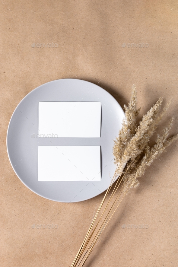 Blank white paper card on plate for mock up with dried spikelets ...
