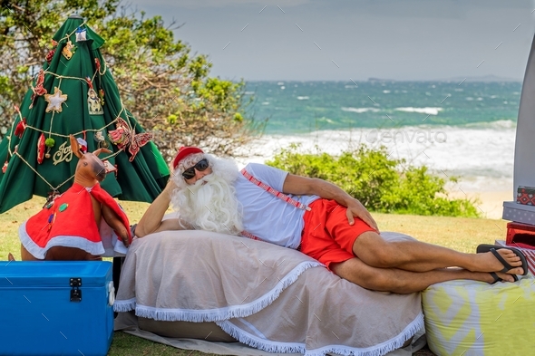 Relaxed Santa Claus lying on the beanbag on the beach with umbrella ...