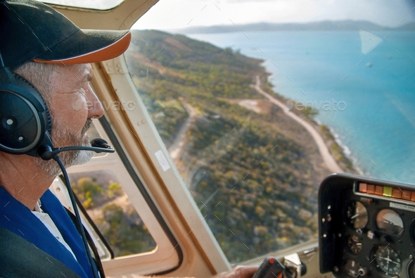 A senior helicopter pilot, man with grey hair and beard flying ...