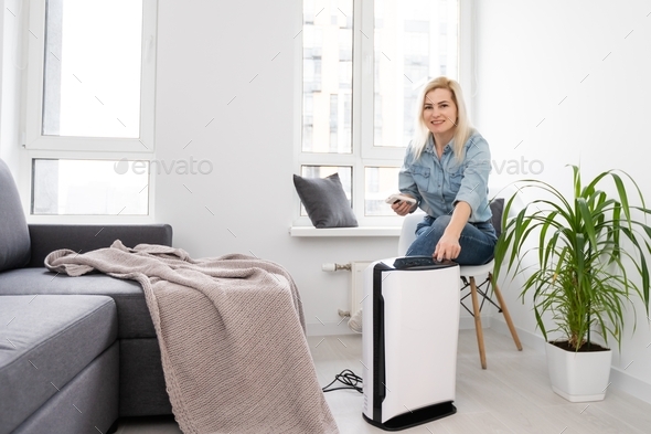 Woman In Living Room Using Air Cleaner And Humidifier Stock Photo by ...