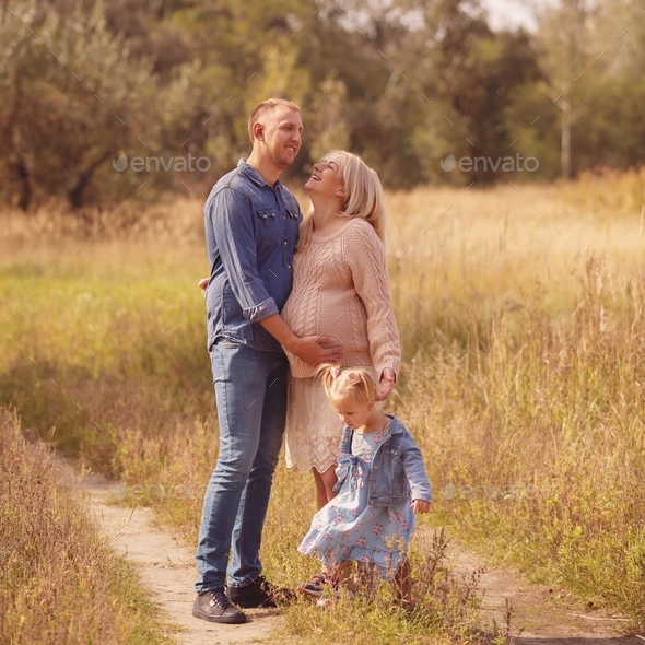Young dad, beautiful pregnant mom and their little cute daughter are ...