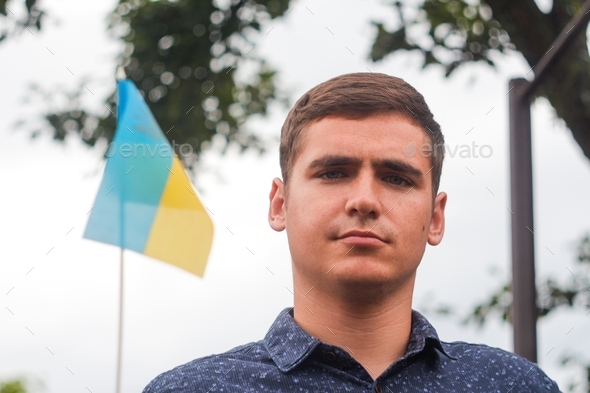 Ukrainian man. Young serious man holding ukrainian flag. No war ...