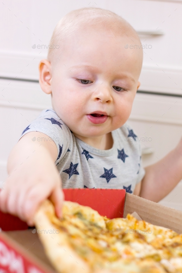 Cute little kid boy taking a slice of pizza. Stock Photo by amihay982