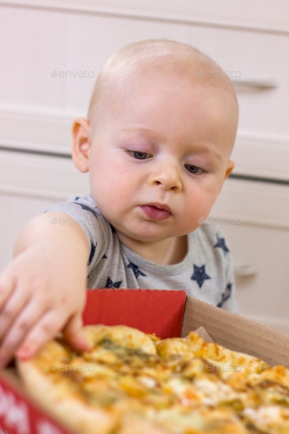 Cute little kid boy taking a slice of pizza. Stock Photo by amihay982