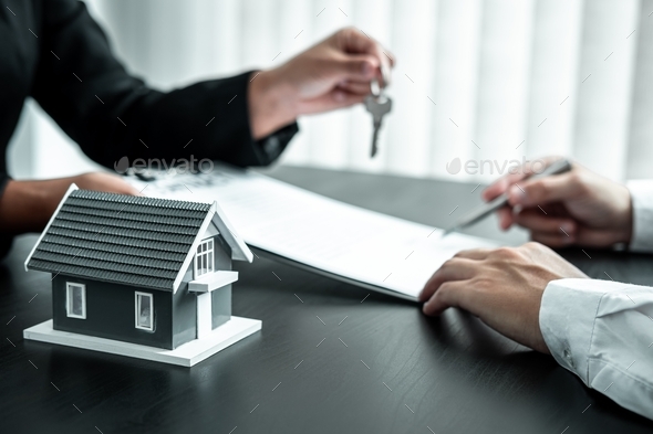 Estate agent giving house model and key to new client after signing ...