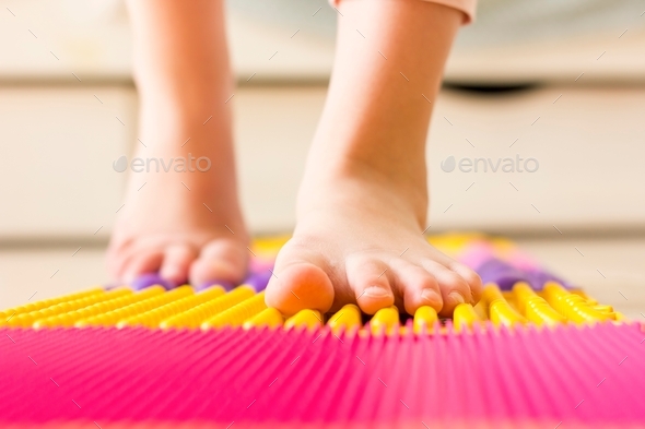 Closeup little girl's feet on orthopedic massage mat. Foot massage for ...