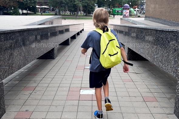 Back to school Happy blonde boy pupil with green backpack goes home ...