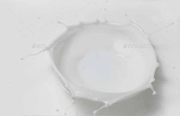 Fresh milk pouring making a crown splash in a milk pool. Top view ...