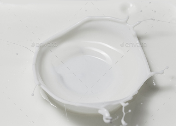 Fresh milk pouring making a crown splash in a milk pool. Top view ...