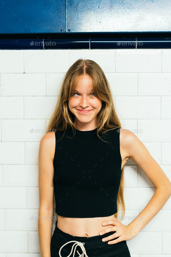Blonde woman leaning down a white brick wall Stock Photo by kikea3