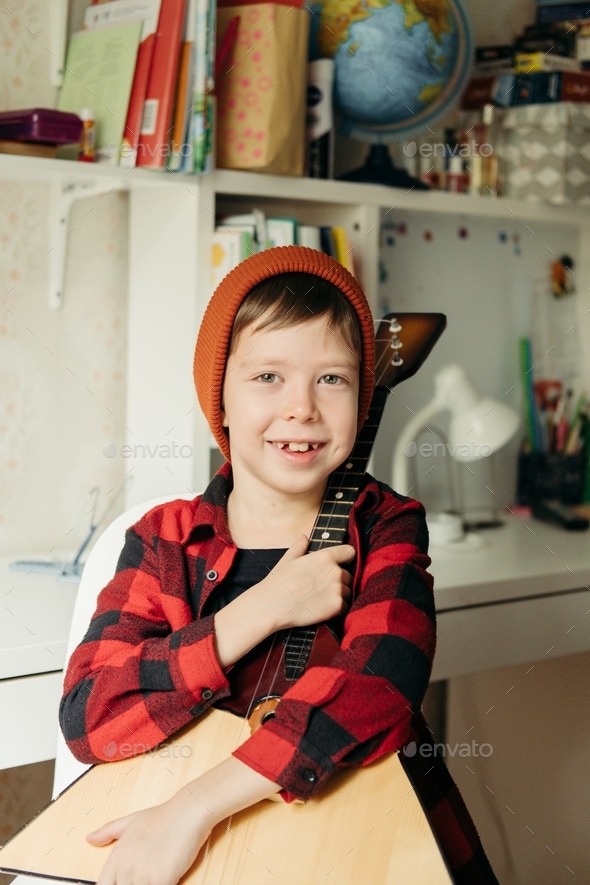 boy in a red hat and a plaid shirt plays the balalaika. Handsome ...