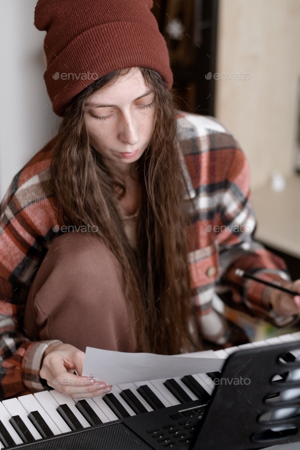 Girl musician in a hat, writes a song with a pencil in her hands ...