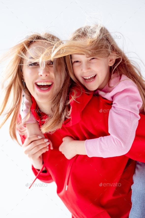 girl on her mother's back, hugs and laughs. Happy mom with her daughter ...