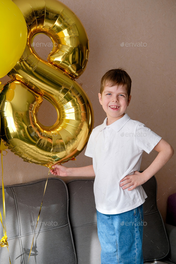 The boy is 8 years old. Happy boy holding golden number eight from ...