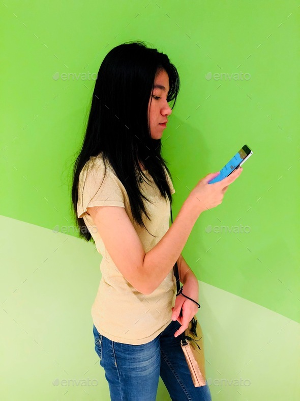 Candid of teenager girl using mobile phone device closeup green texture ...