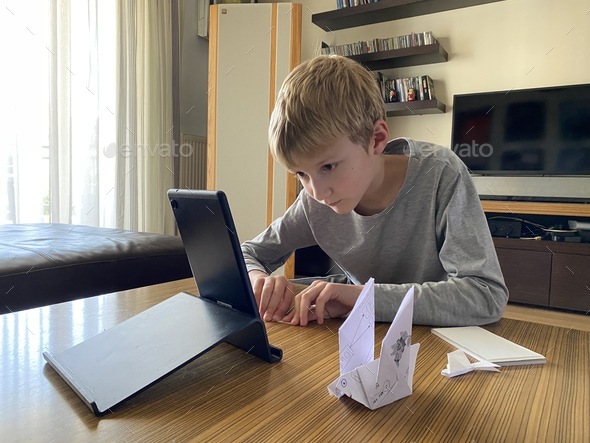 Boy creating origami, online learning Stock Photo by elenabednykh
