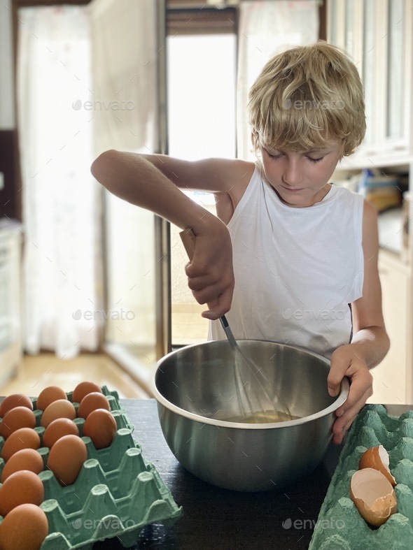 Blonde boy cooking with mother, make omelet, cake, eggs at the kitchen ...