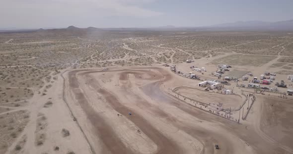 Aerial pan of cars racing on a dirt racetrack in the Mojave Desert ...