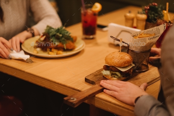 Couple on a date eating burger and fries and salad Stock Photo by laru_ka